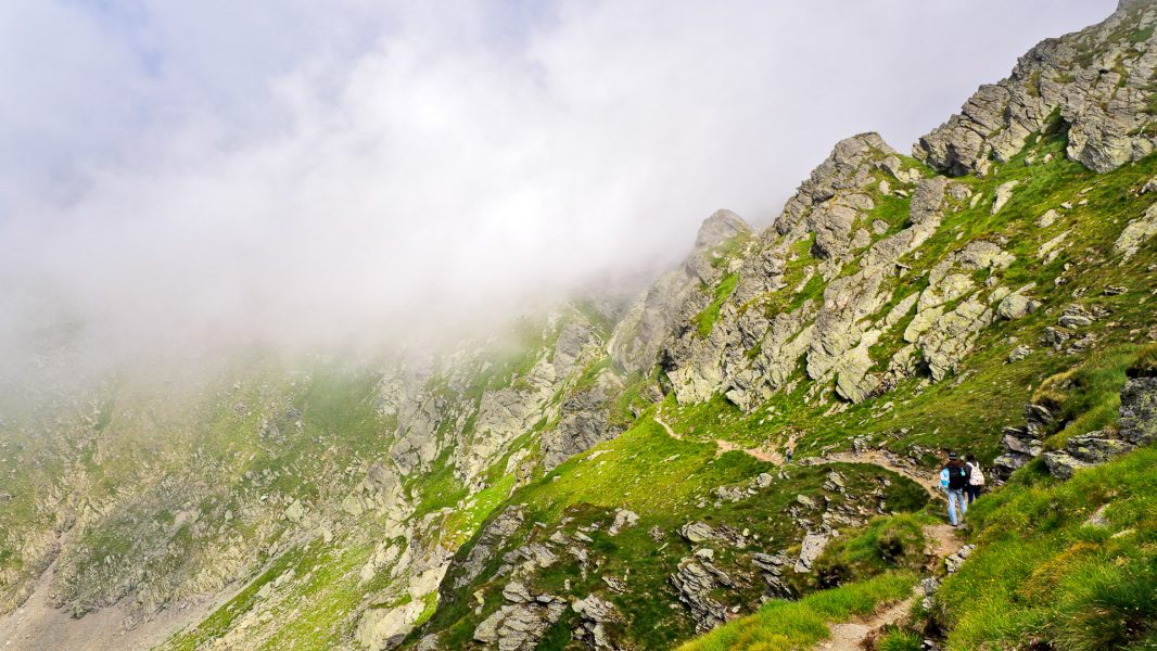 Two hikers on a narrow mountain path - RomaniaTourStore